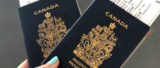 Une main tient deux passeports canadiens